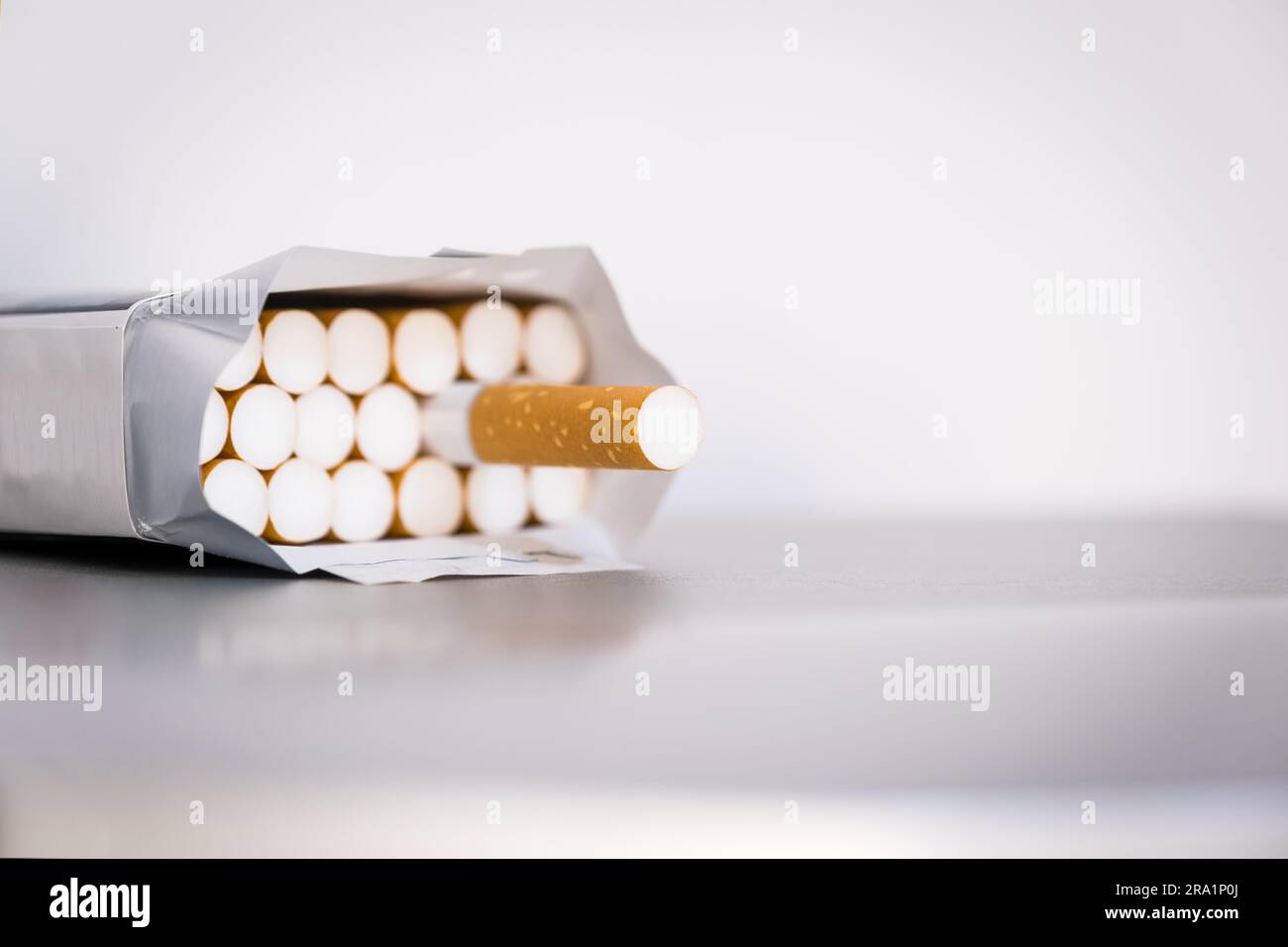 Full open pack of cigarettes stands on glossy tabletop, white ...