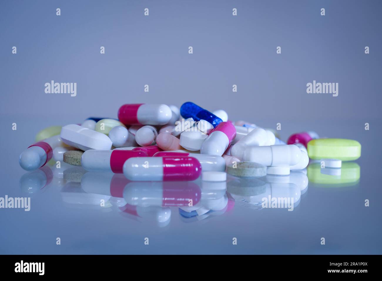 Pile of many capsules and tablets of different color and shapes placed ...