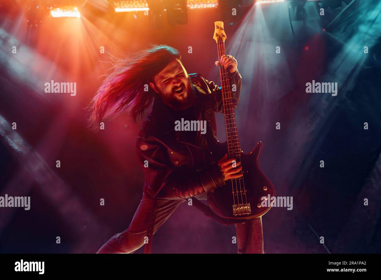 Rock and roll concert. Artistic, expressive man with long hair playing ...