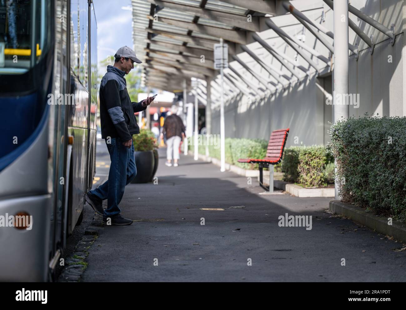 Man checking his smart phone while stepping out of the bus. Bus parked ...