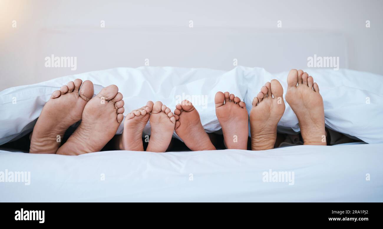 Family, feet in bed and in bedroom of their home with a lens flare ...
