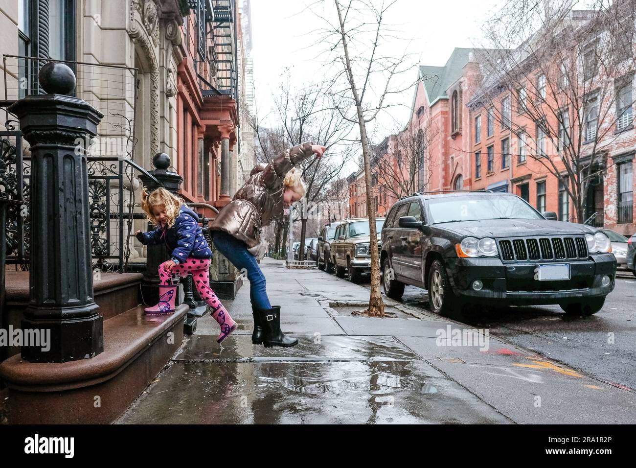 young girls jumping off steps into puddle on rainy day on urban street Stock Photo - Alamy