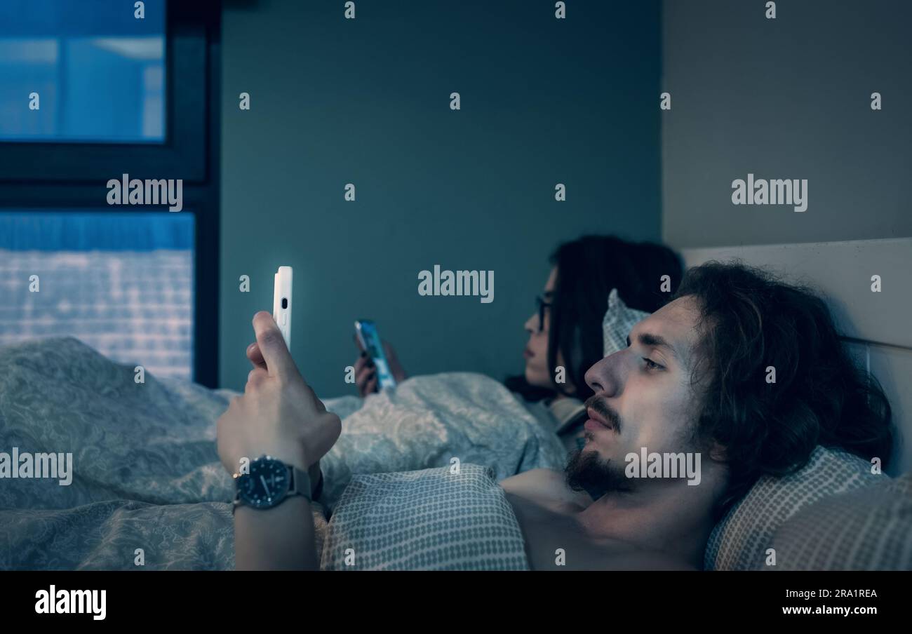 Married couple lying in bed together but each of partners use ...