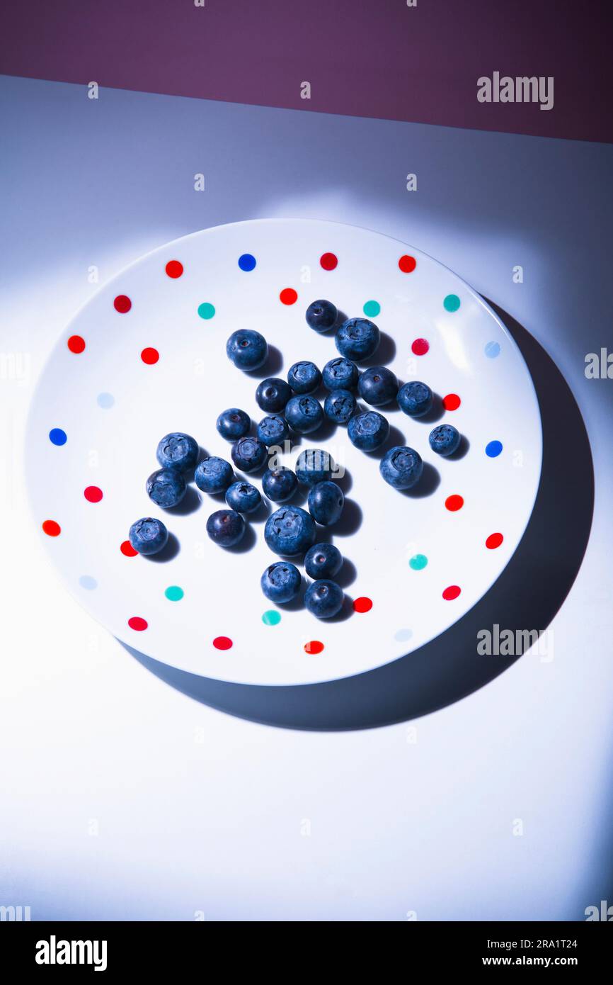 Top view of a dotted plate with blueberries against white table Stock ...
