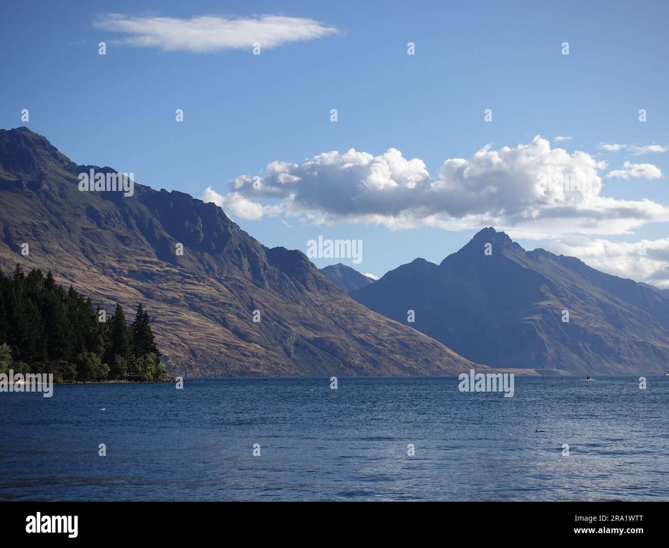 A scenic calm lake water surrounded by majestic mountains in Queenstown ...