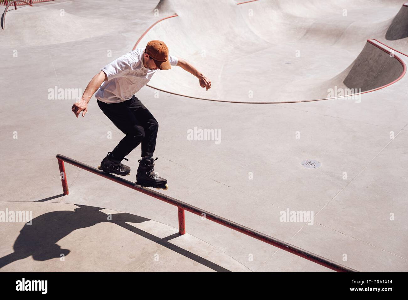 aggressive roller skater performing a trick on a railing in skatepark ...