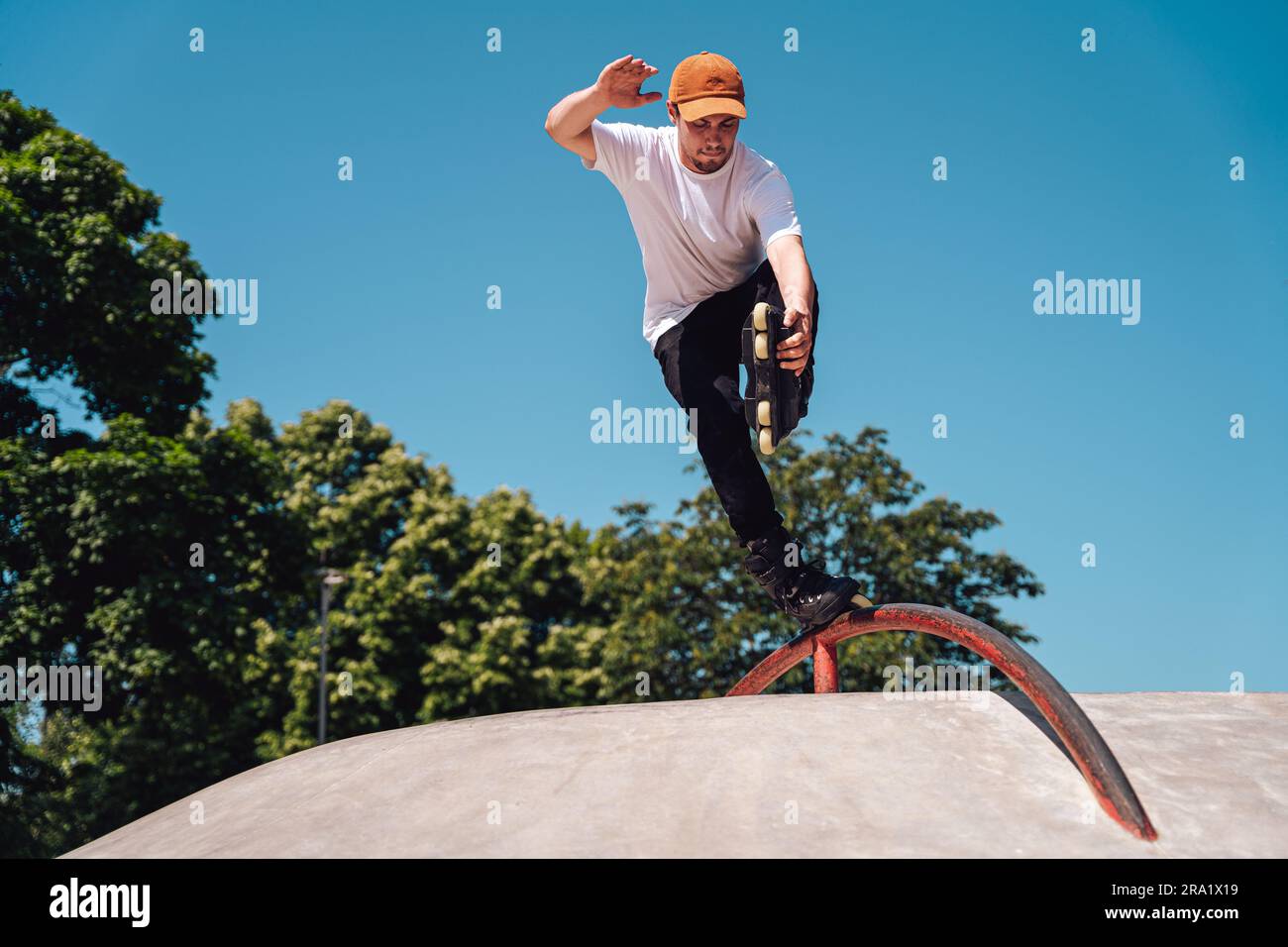 aggressive roller skater performing a trick on a railing in skatepark ...