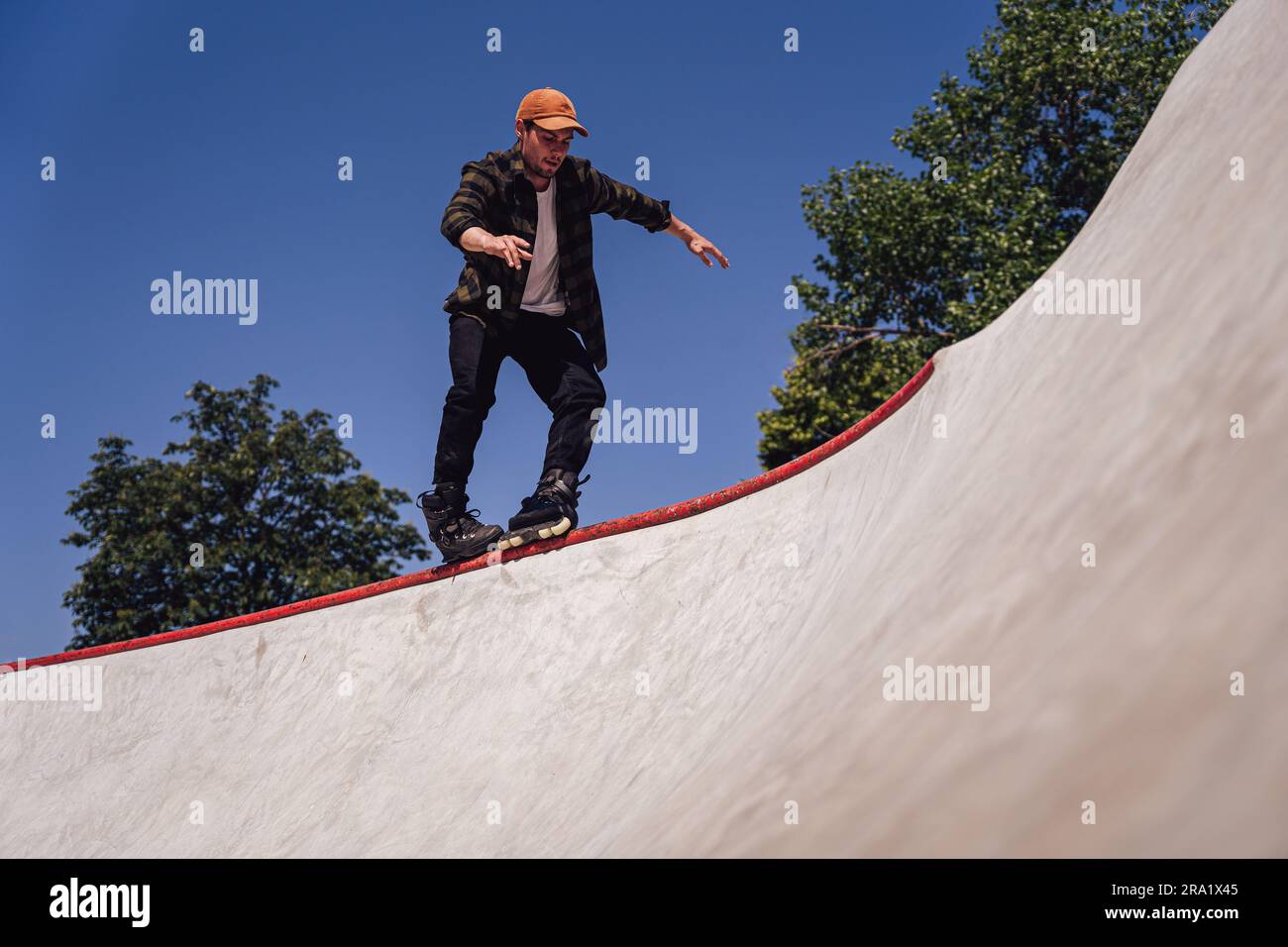 aggressive roller skater performing a trick on a railing in skatepark ...