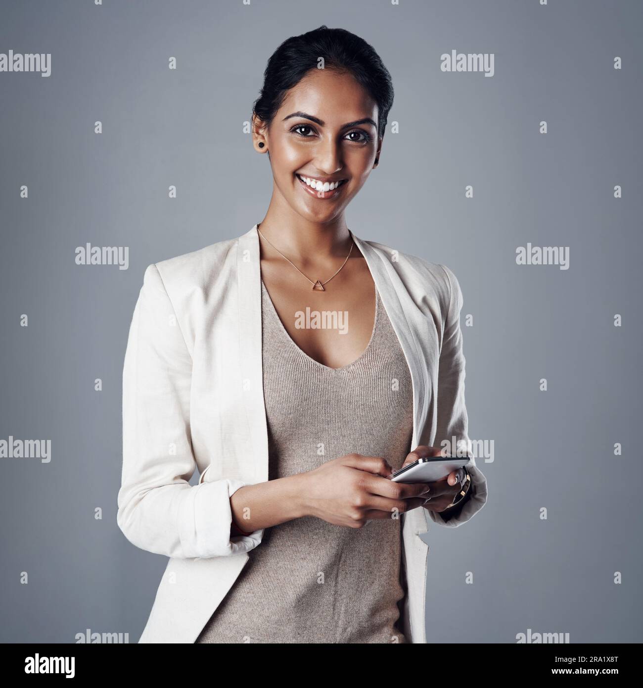 Technology, portrait of a woman with smartphone and against a studio ...