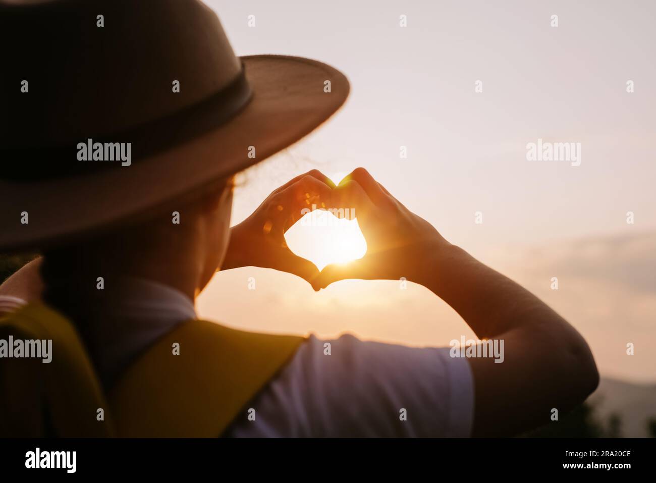 Close up of little girl kid in hat making heart with hands on ...