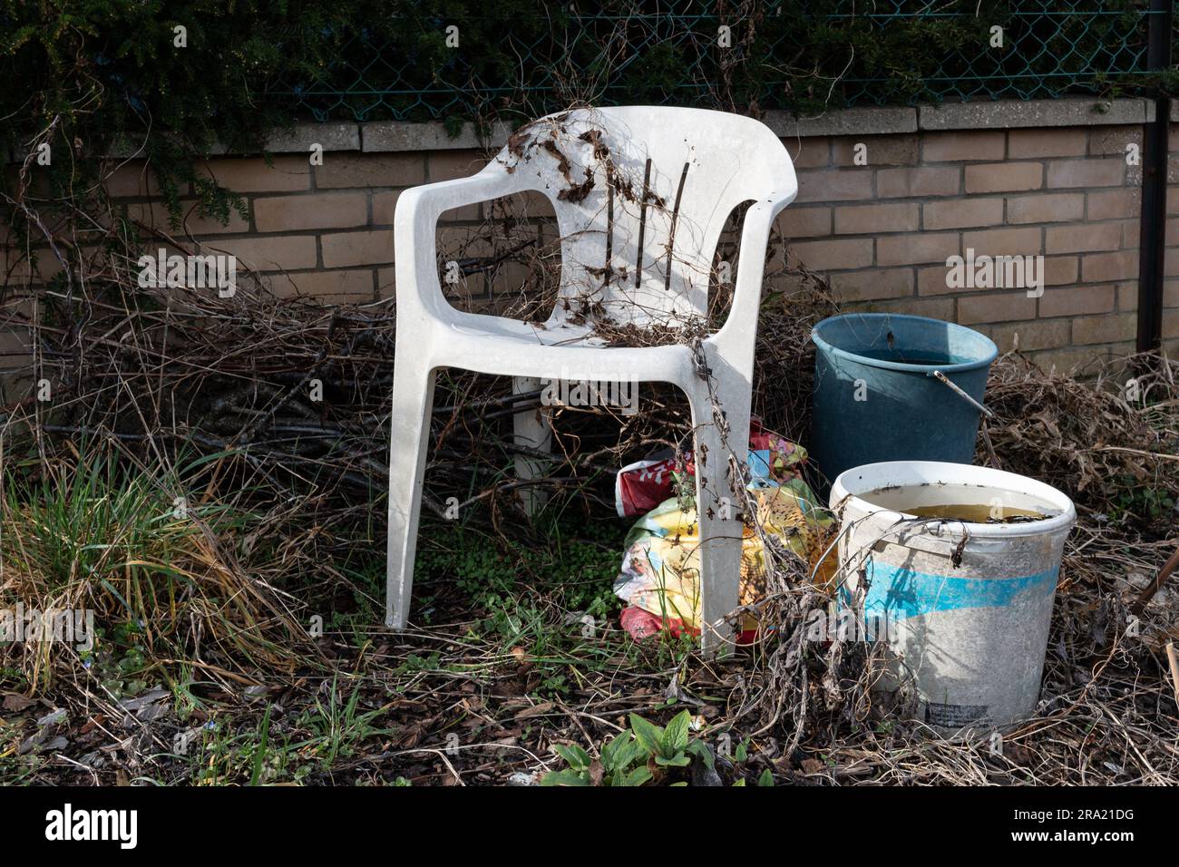 A chair in a messy, overgrown allotment ready for the gardener to sit ...