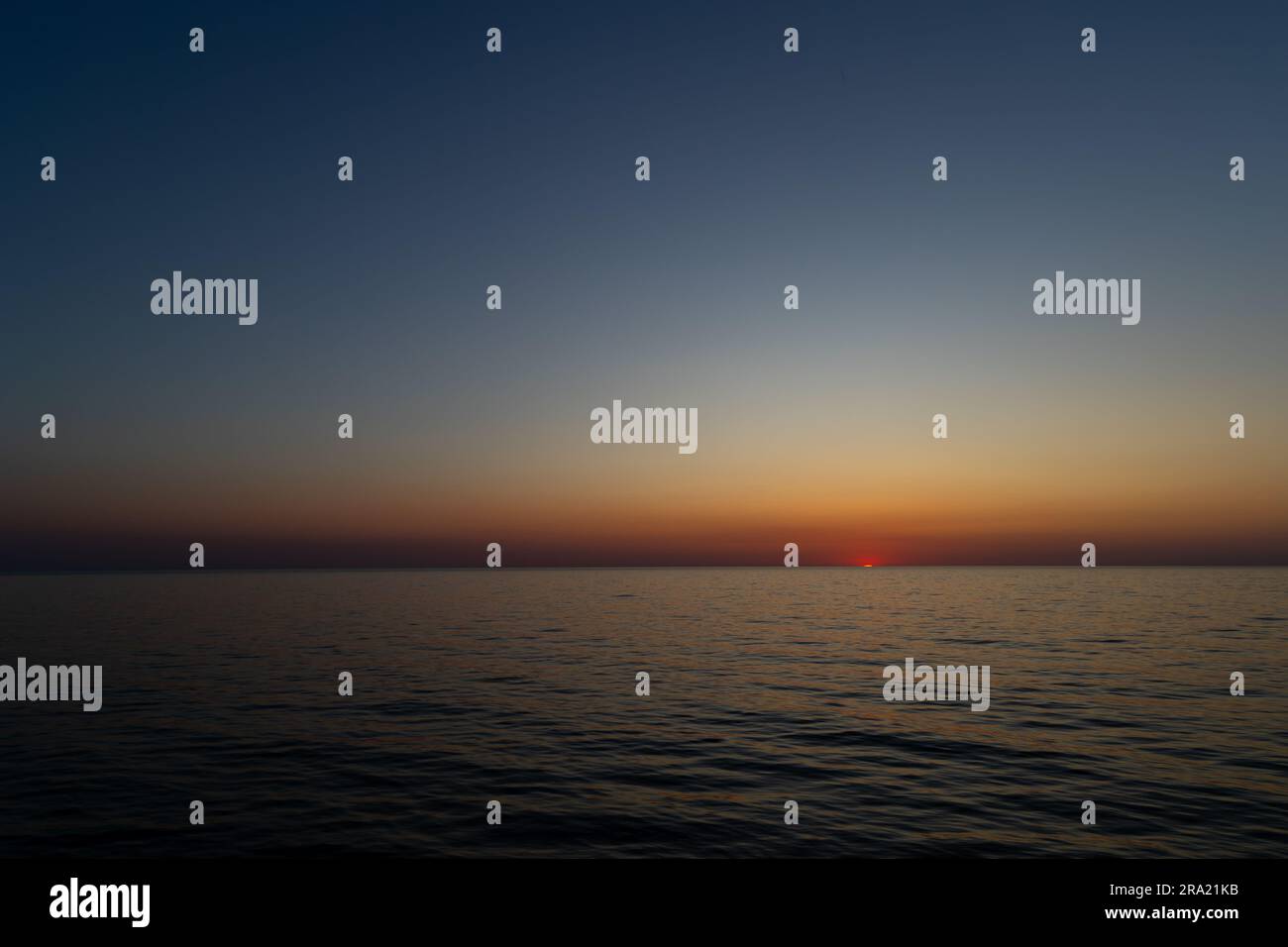 Last rays of the sun setting over a calm sea. Static shot taken during ...