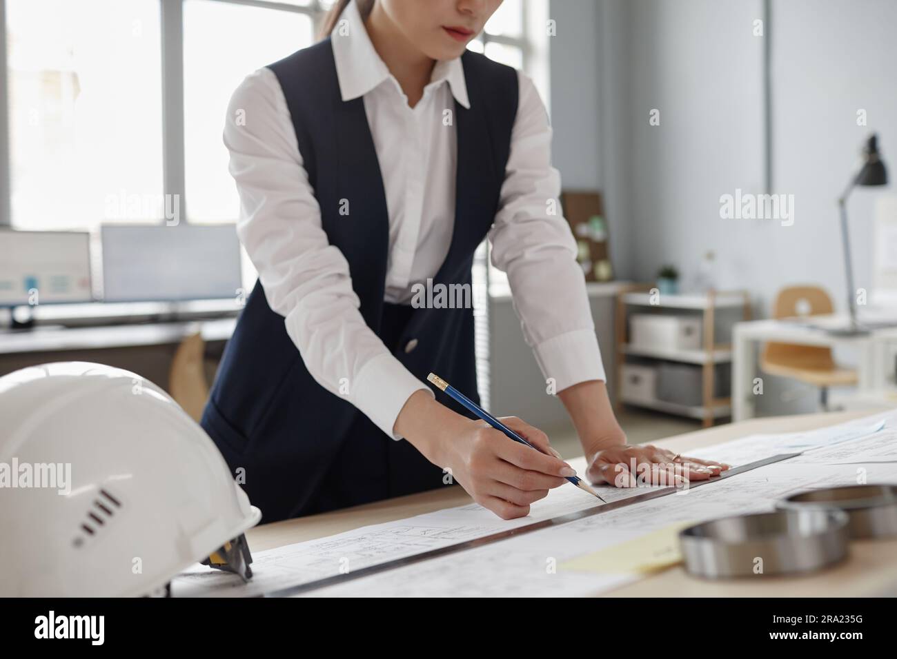 Closeup of female engineer drawing blueprints and plans at workstation ...