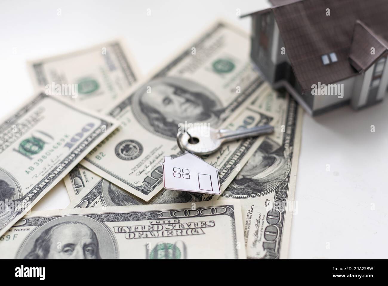 House keys with red house shaped keychain with hundred US dollars Stock ...