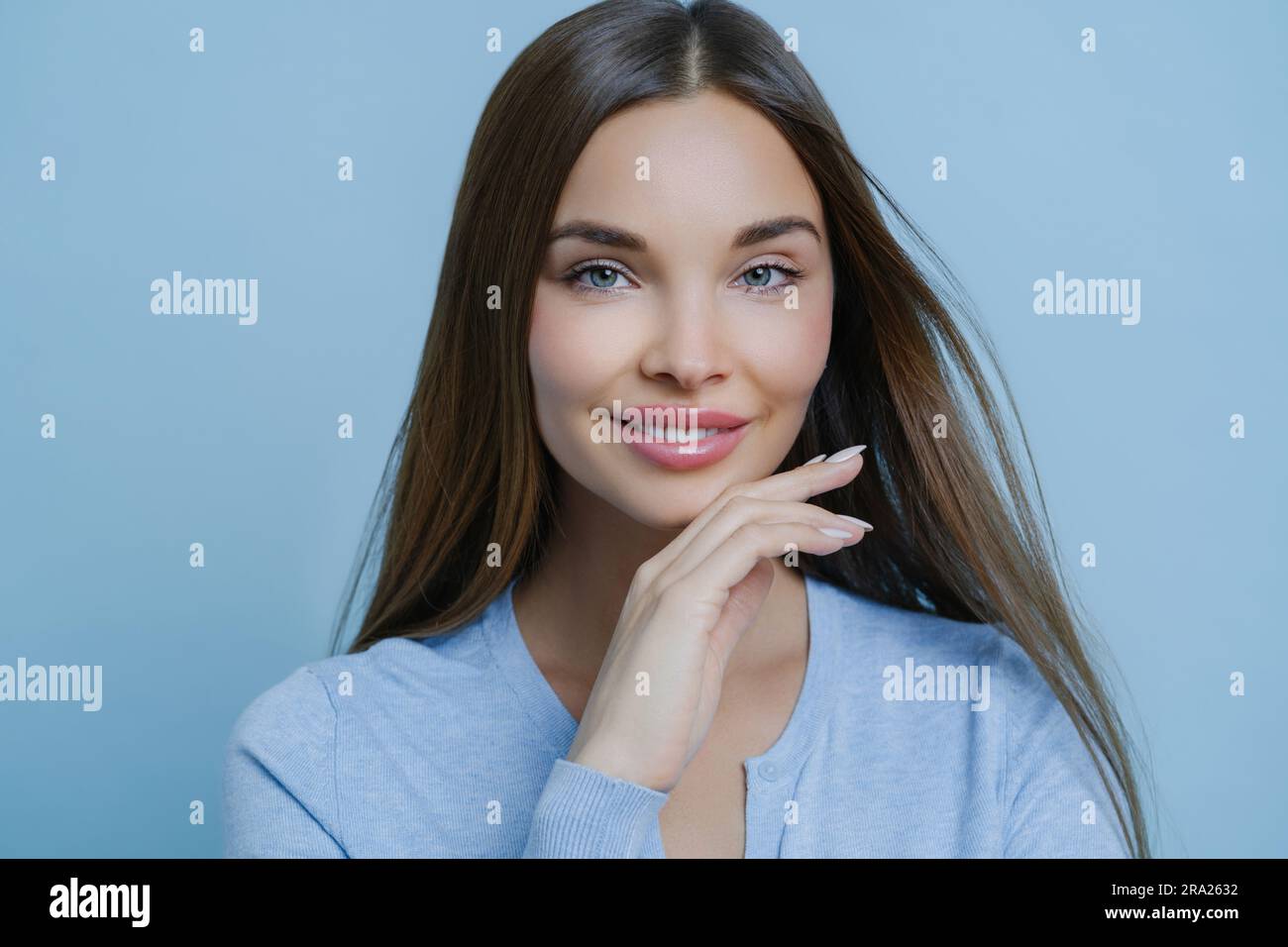 Alluring model touches jawline, smiles with perfect skin, minimal ...