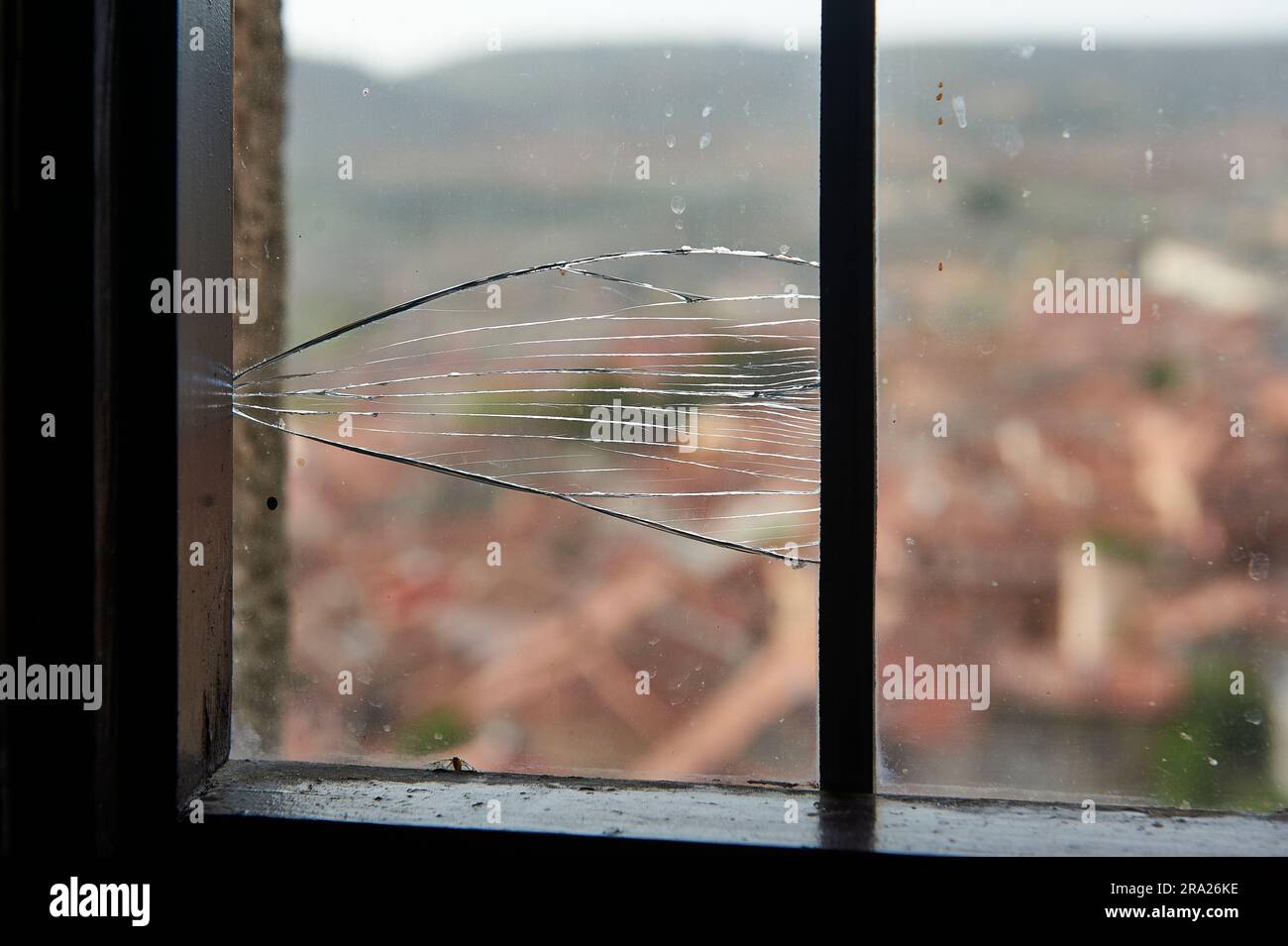 A close-up image of a building featuring broken glass within the window ...
