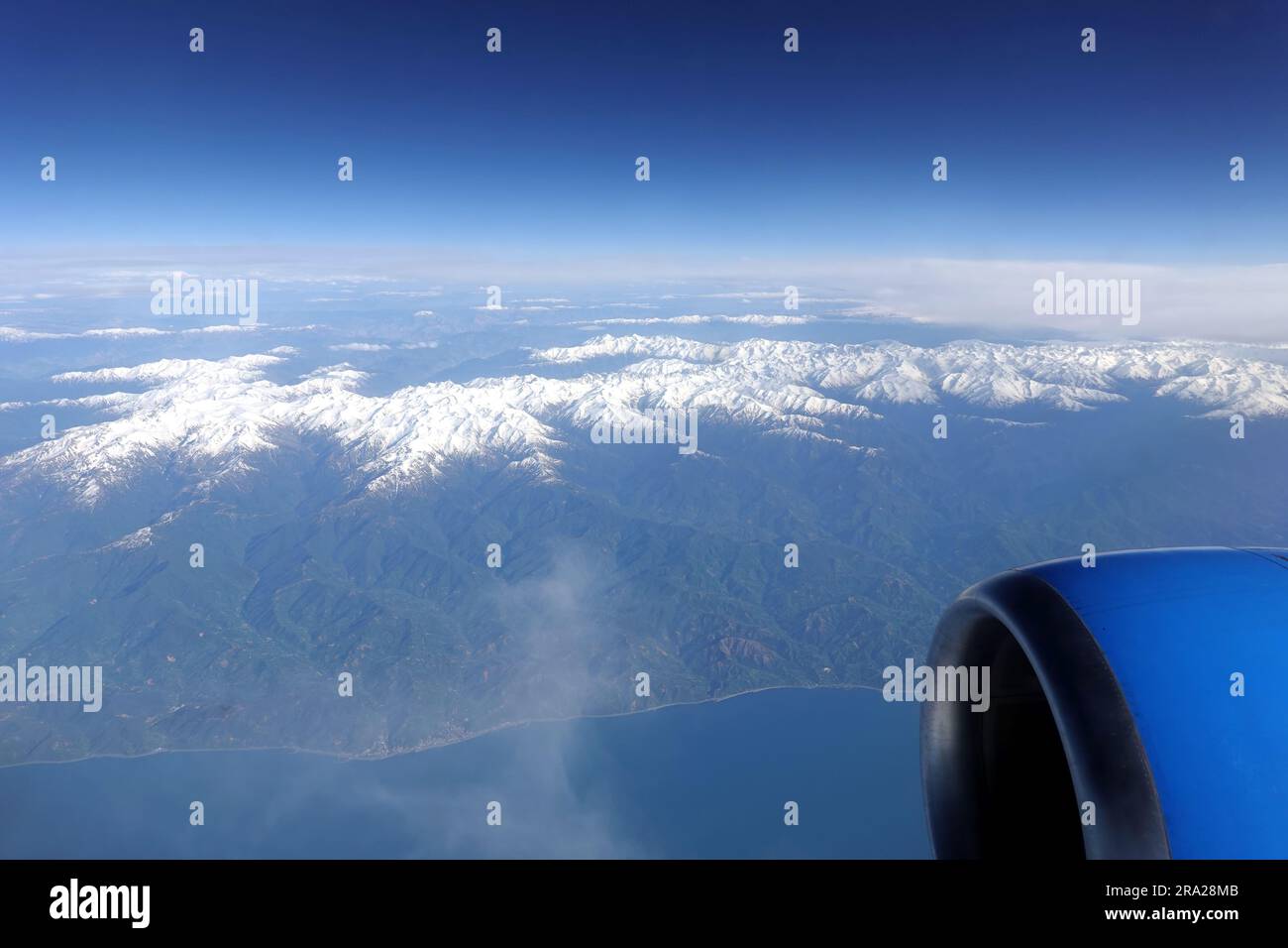 View to the sea coastline and high snow-capped mountains peaks and blue sky till horizon from ...