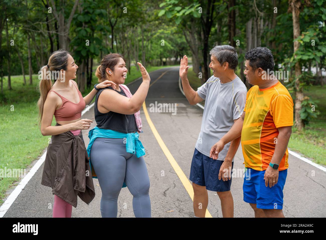 A group of 2 male and 2 female runners giving each other high five to ...