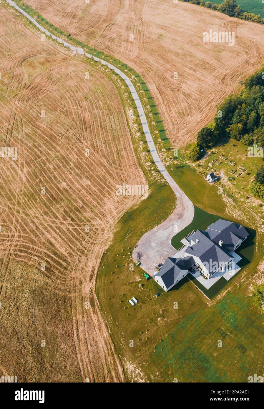 An aerial shot of a large two-story house stands in a vast grassy field ...