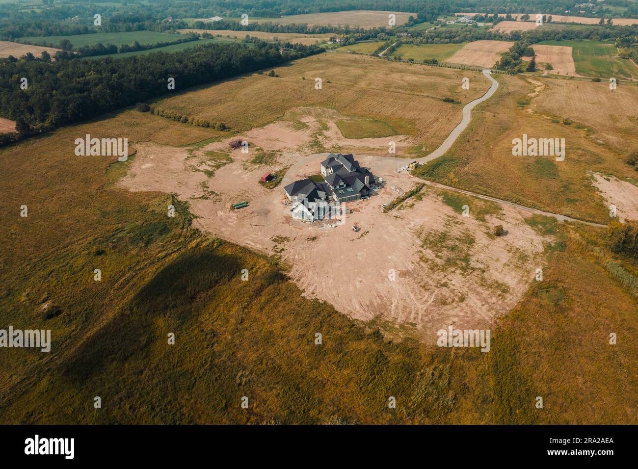 An aerial shot of a large two-story house stands in a vast grassy field ...