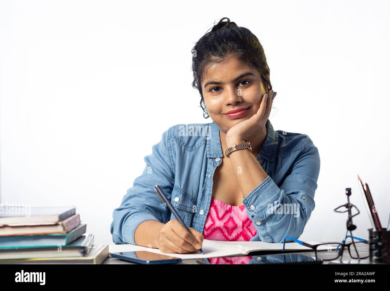 A pretty young Indian college student studying and looking at camera on ...
