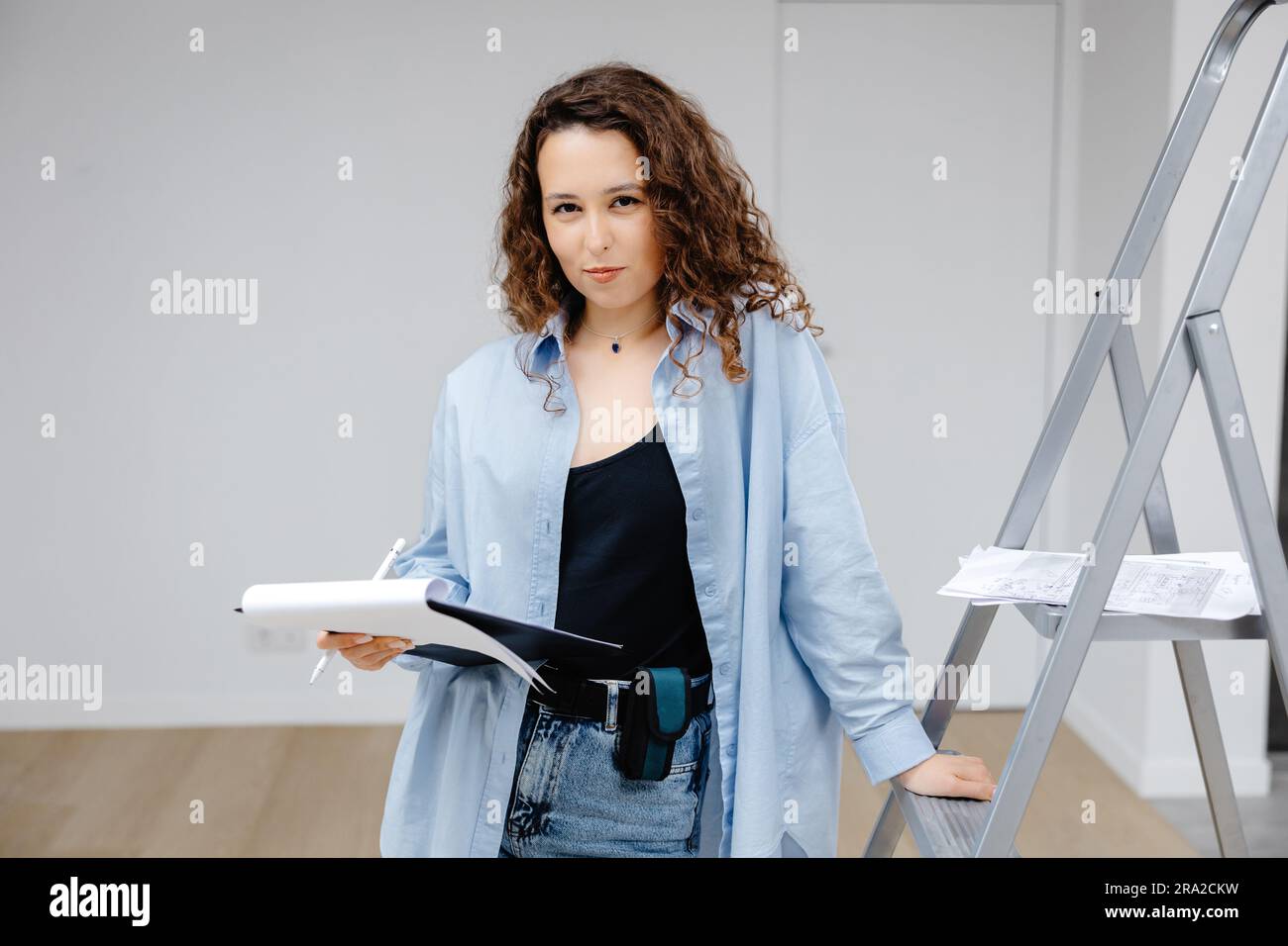 A young pretty girl designer keeps documents while standing at her ...