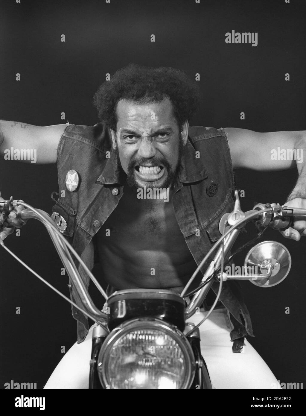 Close-up of a man in a in a cut off jeans vest With his hands on the ...