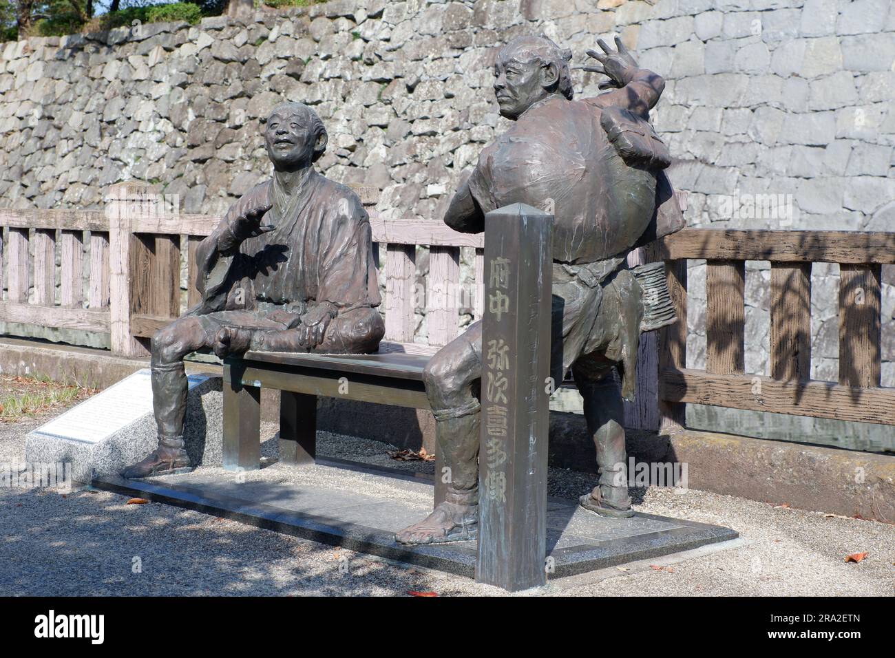 A bronze statue of two men seated on a bench in a park Stock Photo - Alamy