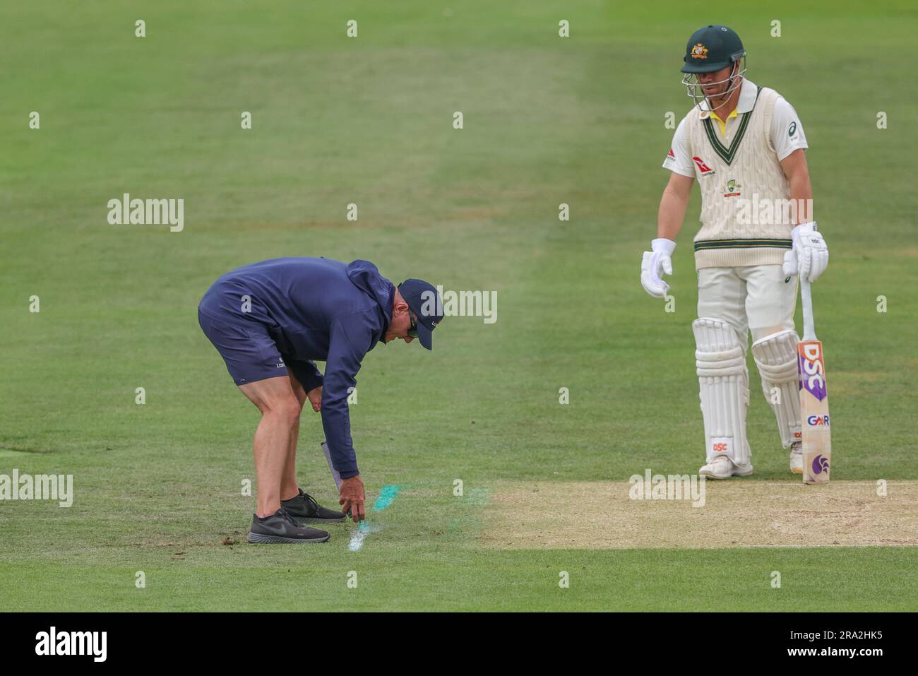 Ground staff paint over a previously marked white line with green paint ...