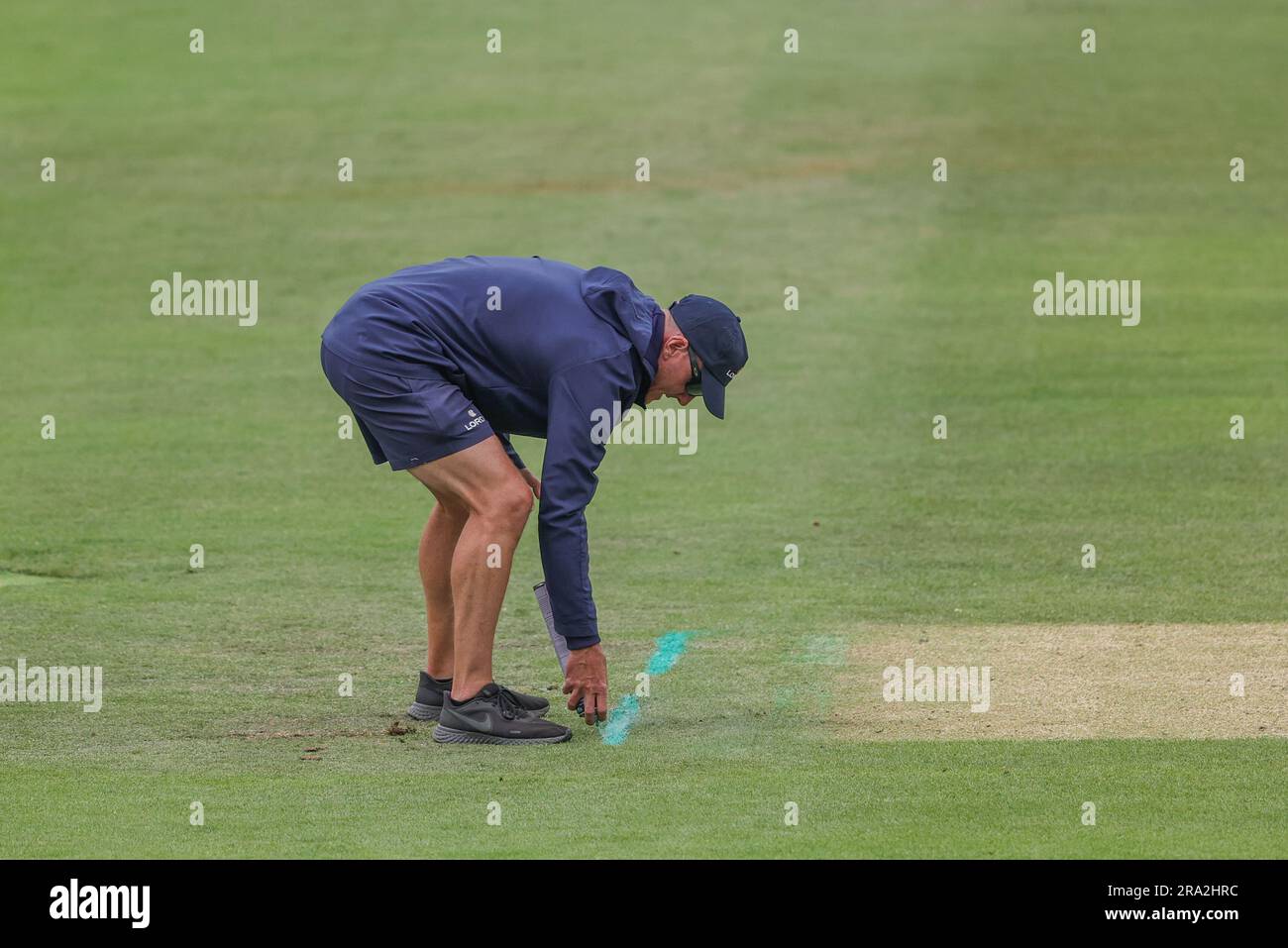 Ground staff paint over a previously marked white line with green paint ...