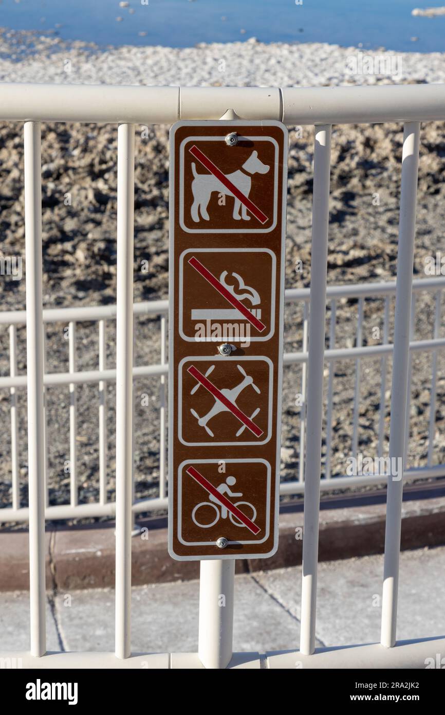 A wooden beach sign with white lettering displaying prohibited items ...