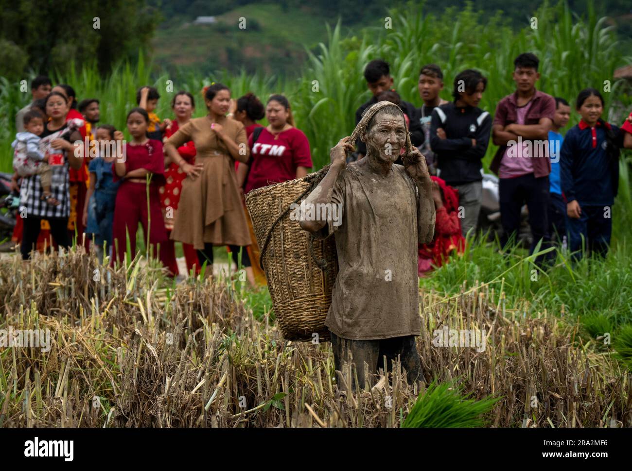 People gather to watch others playing in the mud in a paddy field on ...