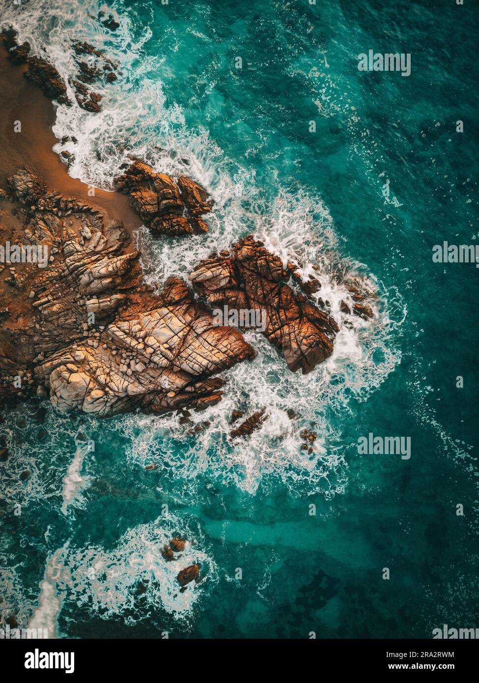 An aerial view of the coastline with beautiful waves and color contrast ...