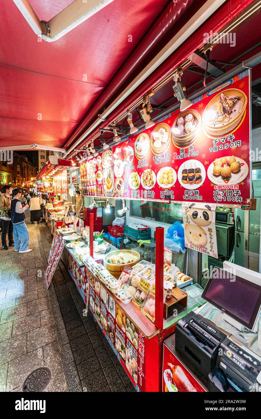 Night-time street scene along row of Chinese food stalls selling ...