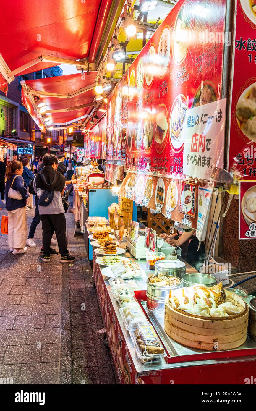 Night-time street scene along row of Chinese food stalls selling ...