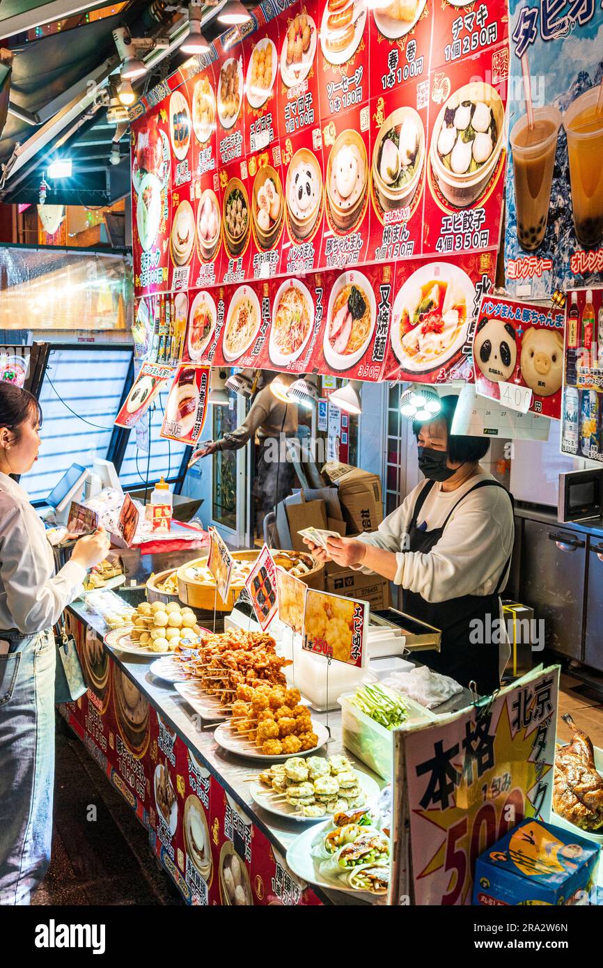 Woman serving young woman at a Chinese food stall selling foods on a ...