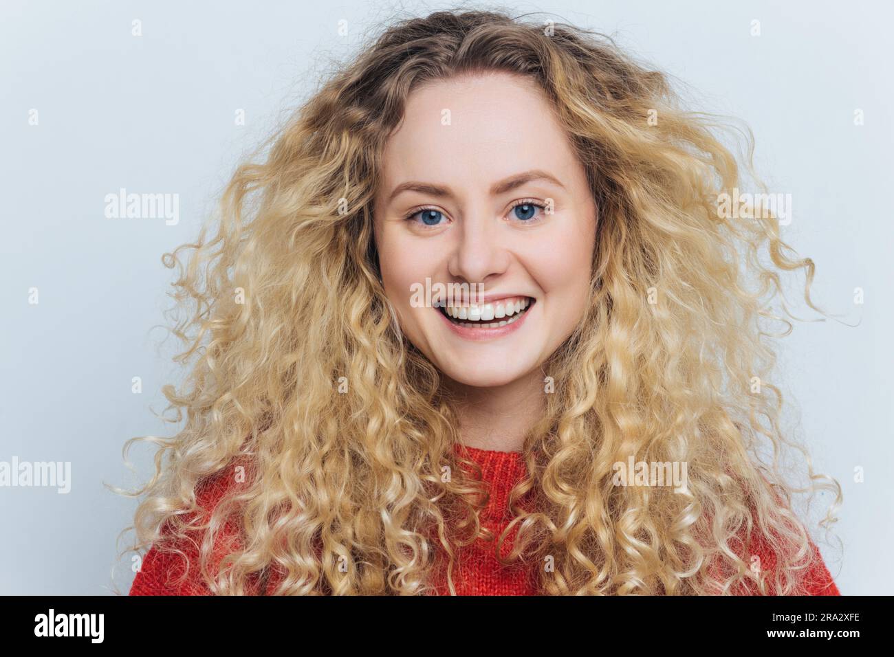 Curly-haired woman with glowing skin, wide smile, perfect teeth ...