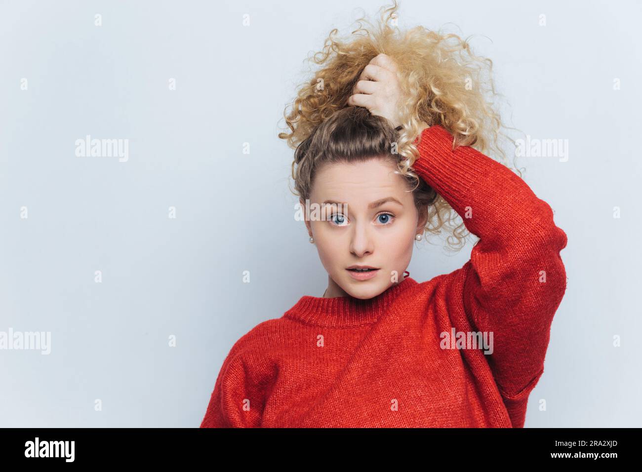 Blue-eyed woman in red sweater, stunned expression, isolated on white ...