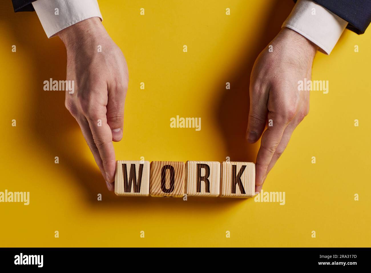 The word WORK is written in wooden cubes in black letters on a yellow ...