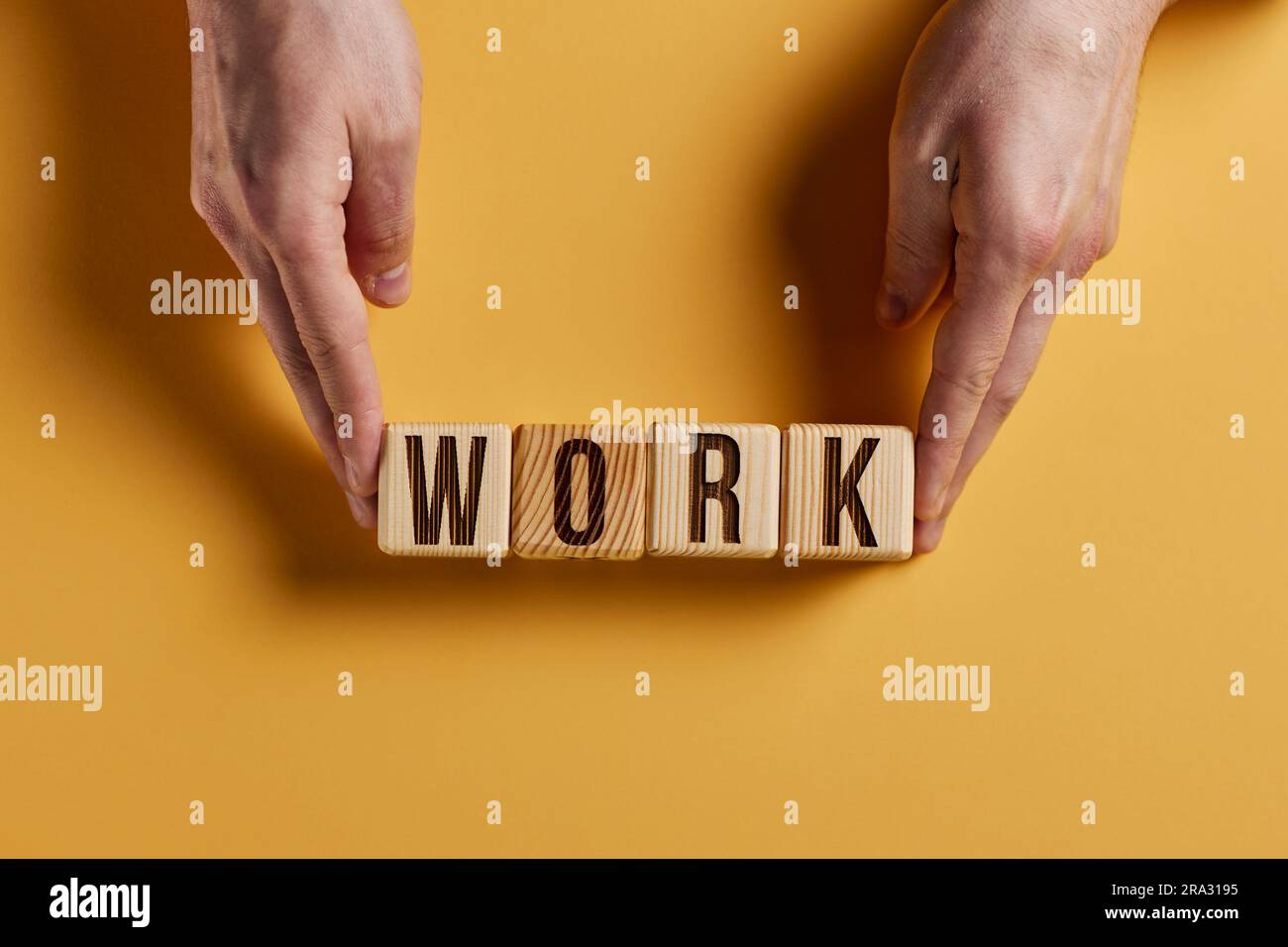The word WORK is written in wooden cubes in black letters on a yellow ...