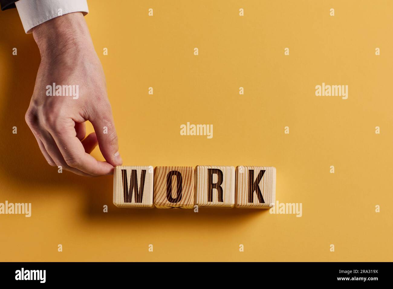 The word WORK is written in wooden cubes in black letters on a yellow ...