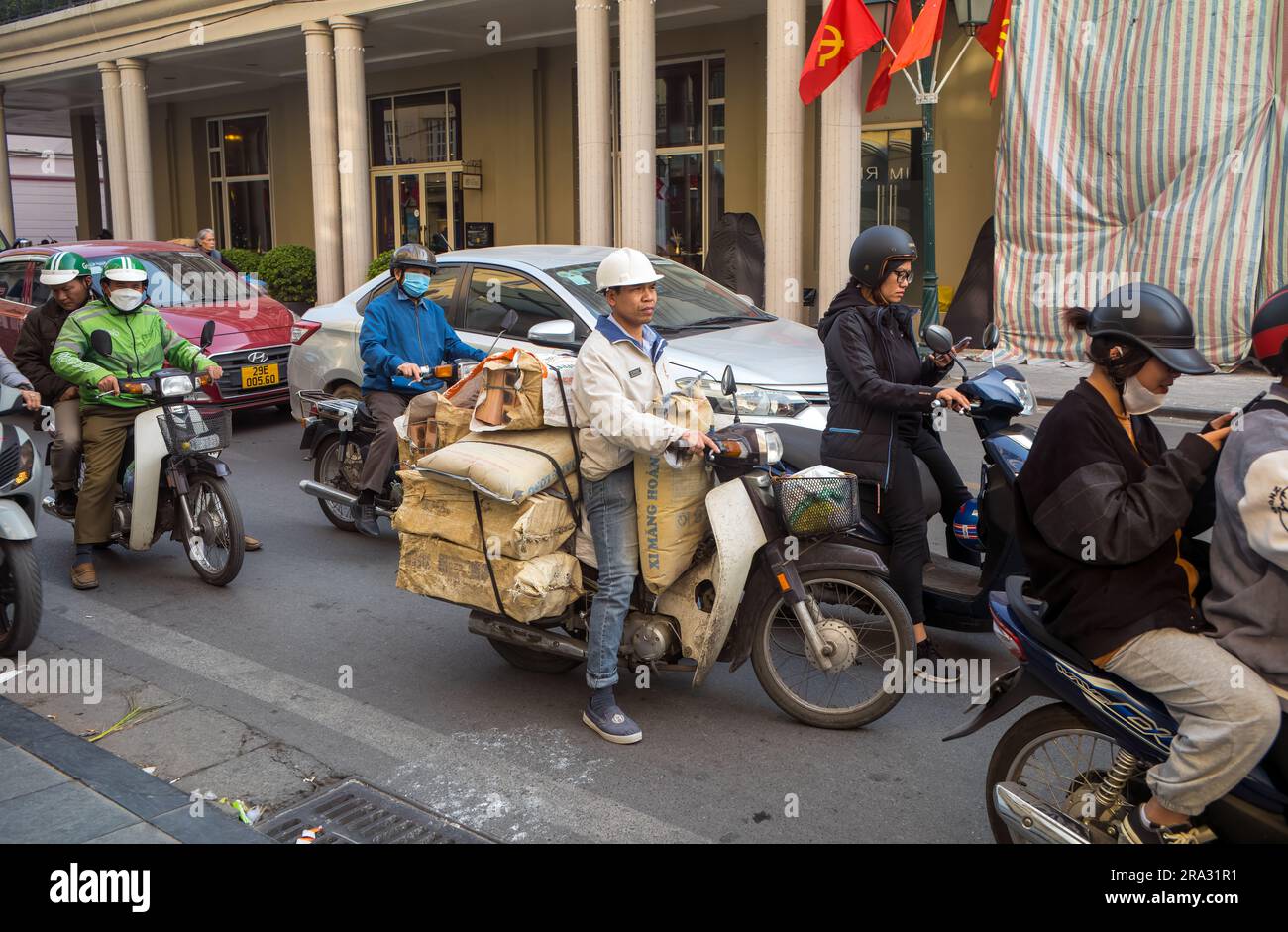A Vietnamese man sits on a motorcycle scooter overloaded with sacks of ...
