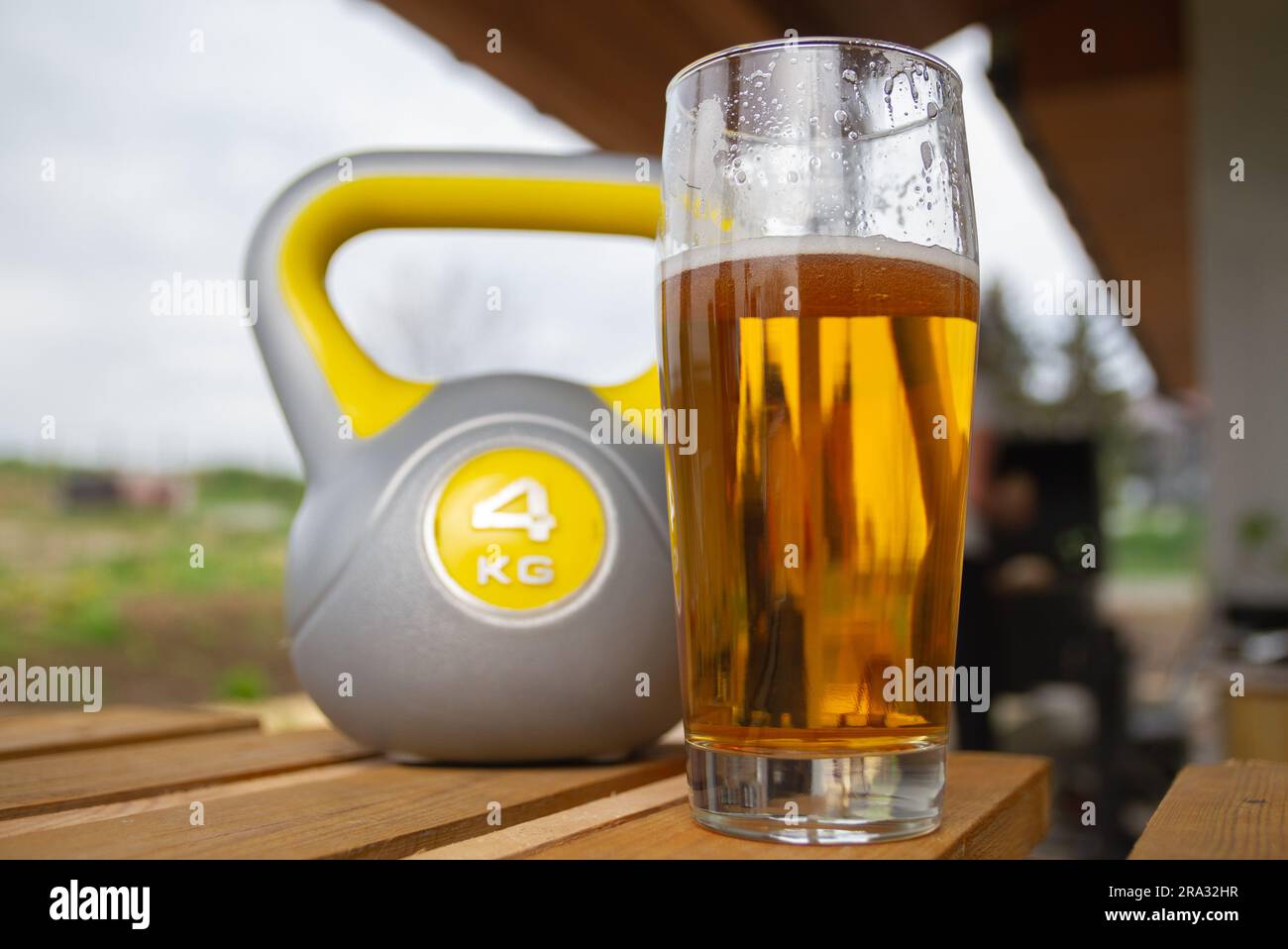 Glass of beer and heavy gym kettlebell weight. Contrasting alcohol with ...