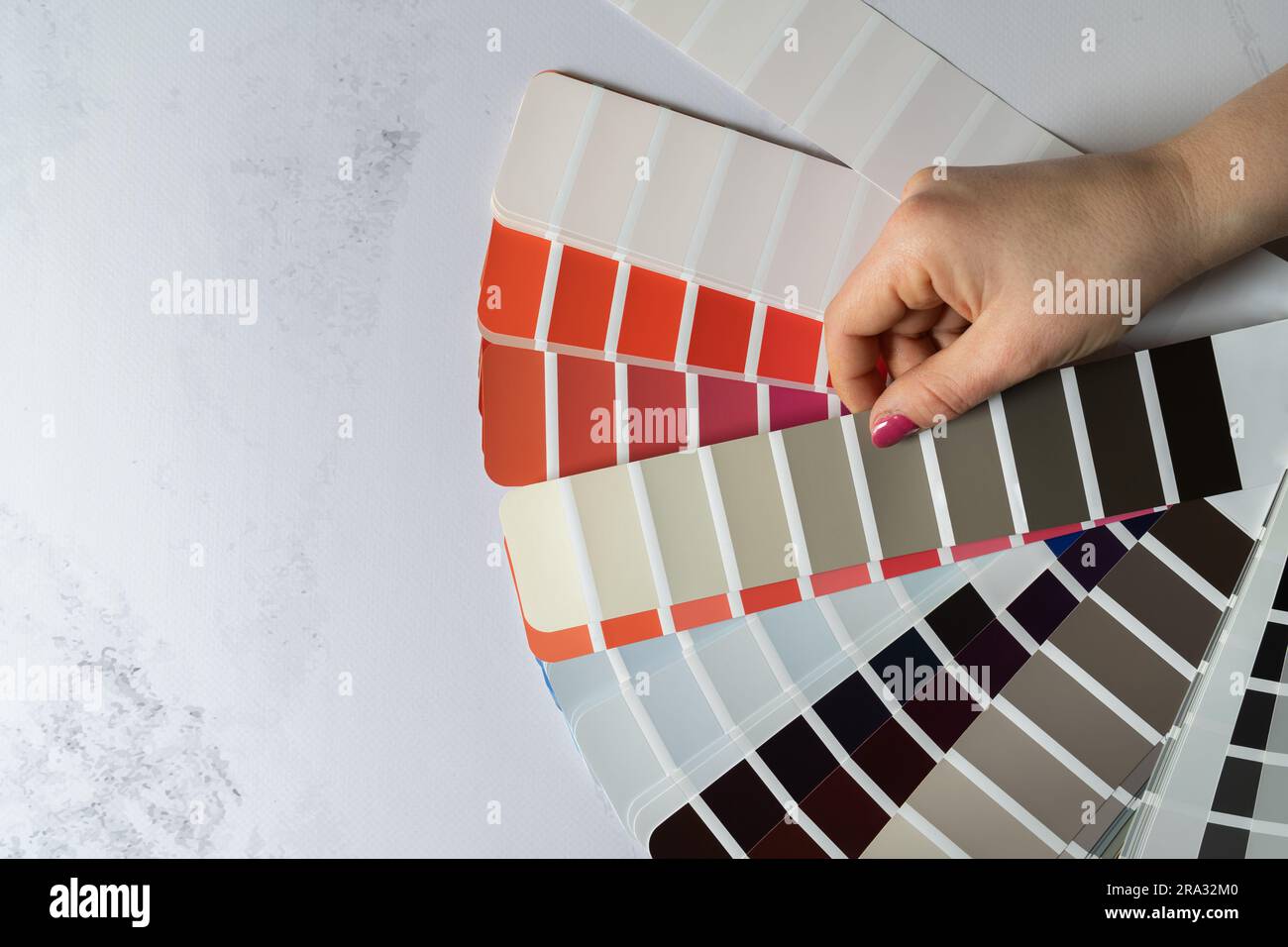 Female hand holding color palette guide catalog with colour swatches ...