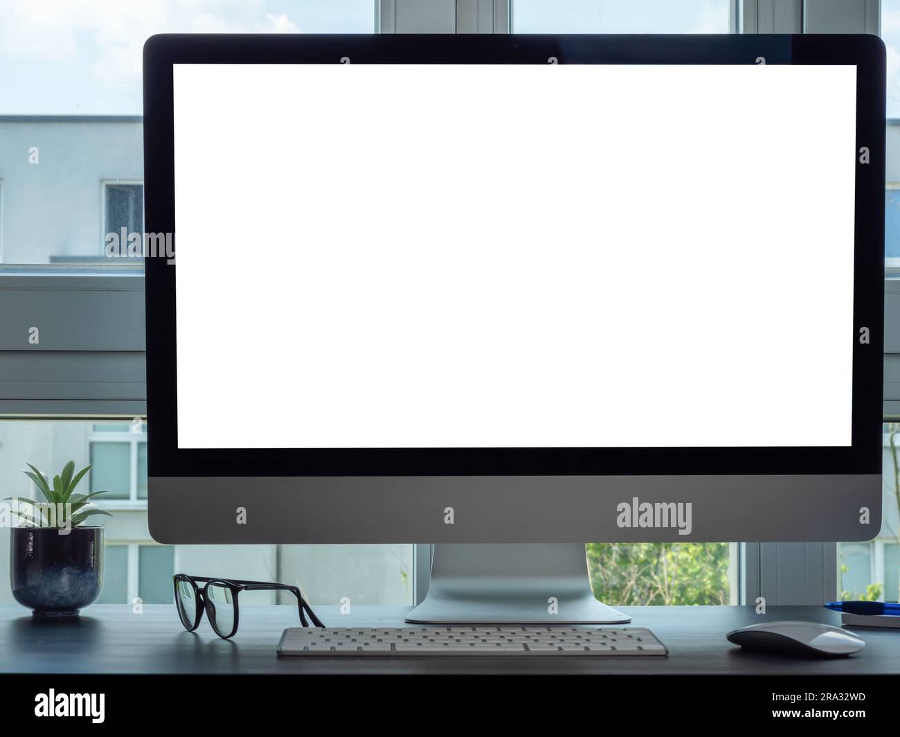 The computer is on the desk by the window. The computer has a white ...