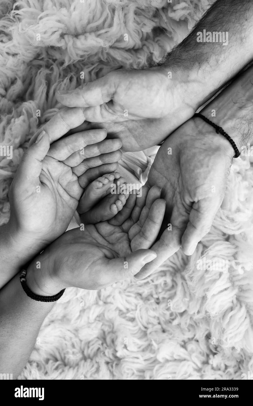 The palms of the father and mother are holding the foot of the newborn ...