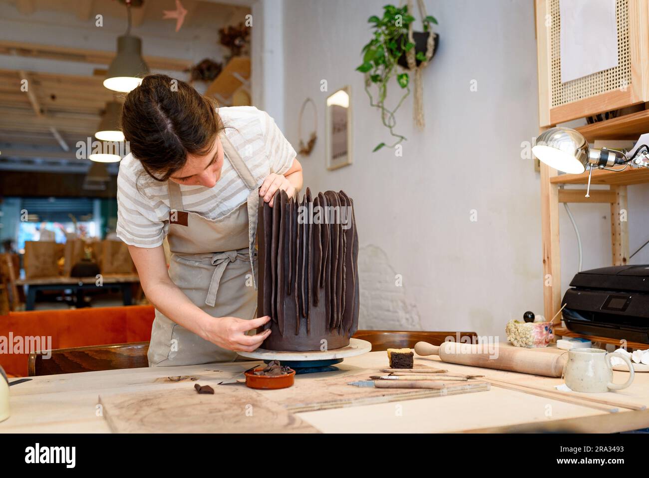woman in pottery workshop working raw ceramic vase and clay to make pot ...