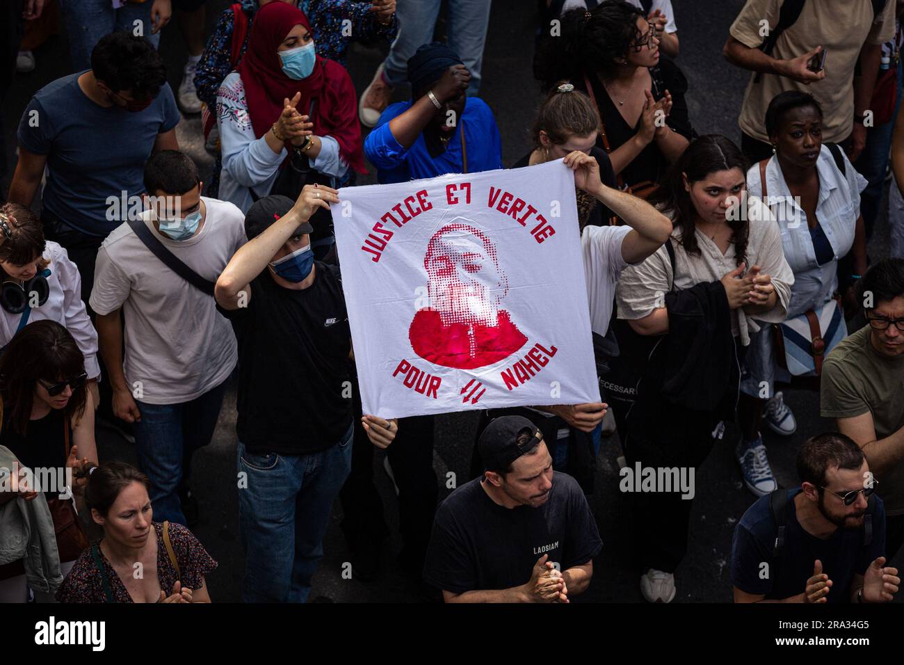 Protesters march with a flag that says "Justice and truth for Nahel ...