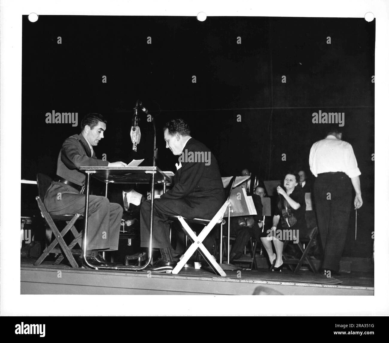 Photograph of Two Men (One in Military Uniform) Seated and Talking into ...