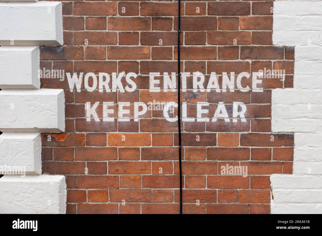 Works entrance, keep clear painted on a red brick wall Stock Photo - Alamy